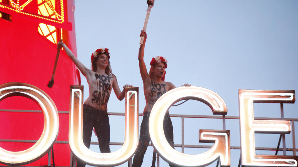 Topless Femen protestors climb Moulin Rouge in Paris